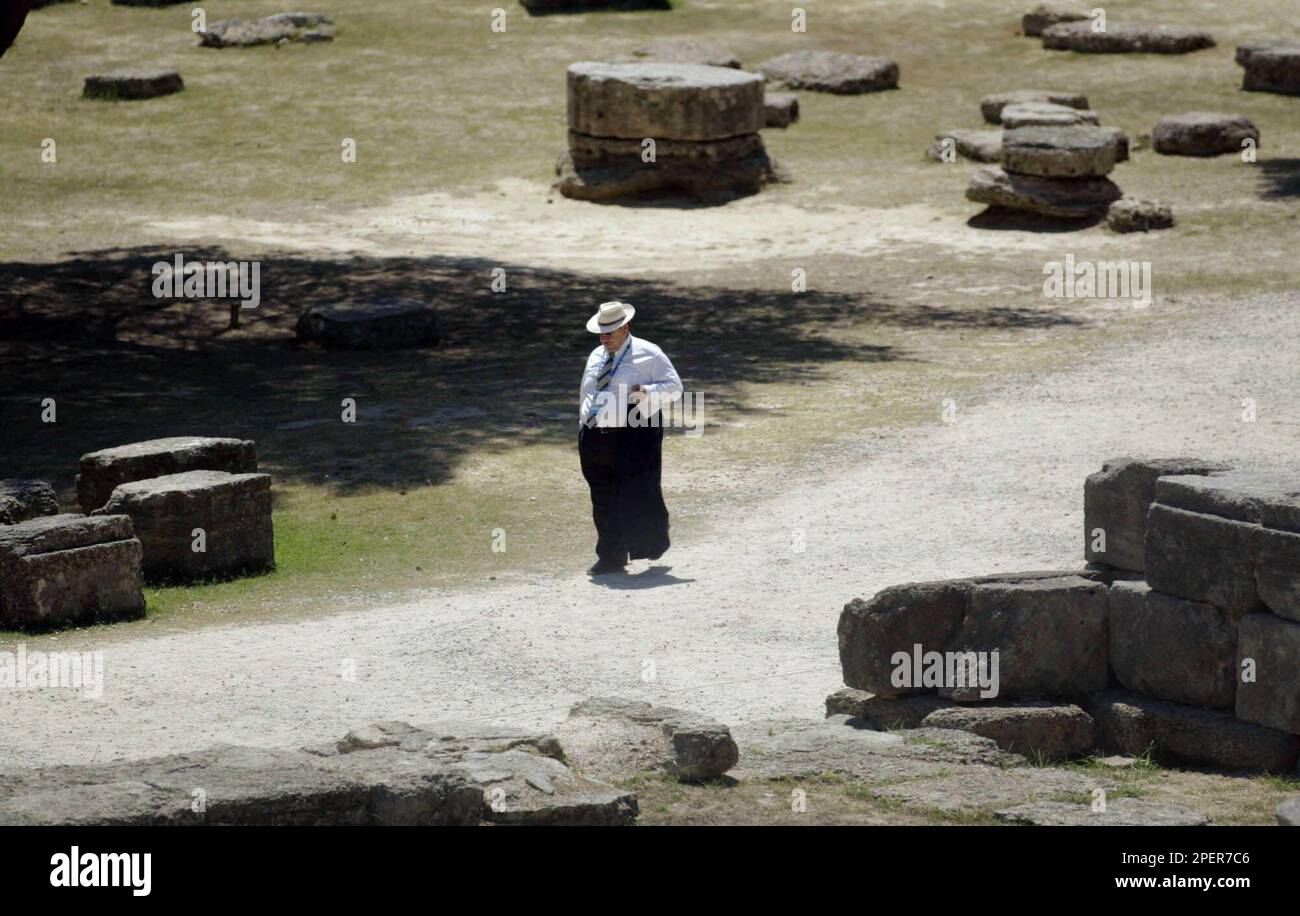 An Olympic shot put judge walks among the ruins of the site of the ...