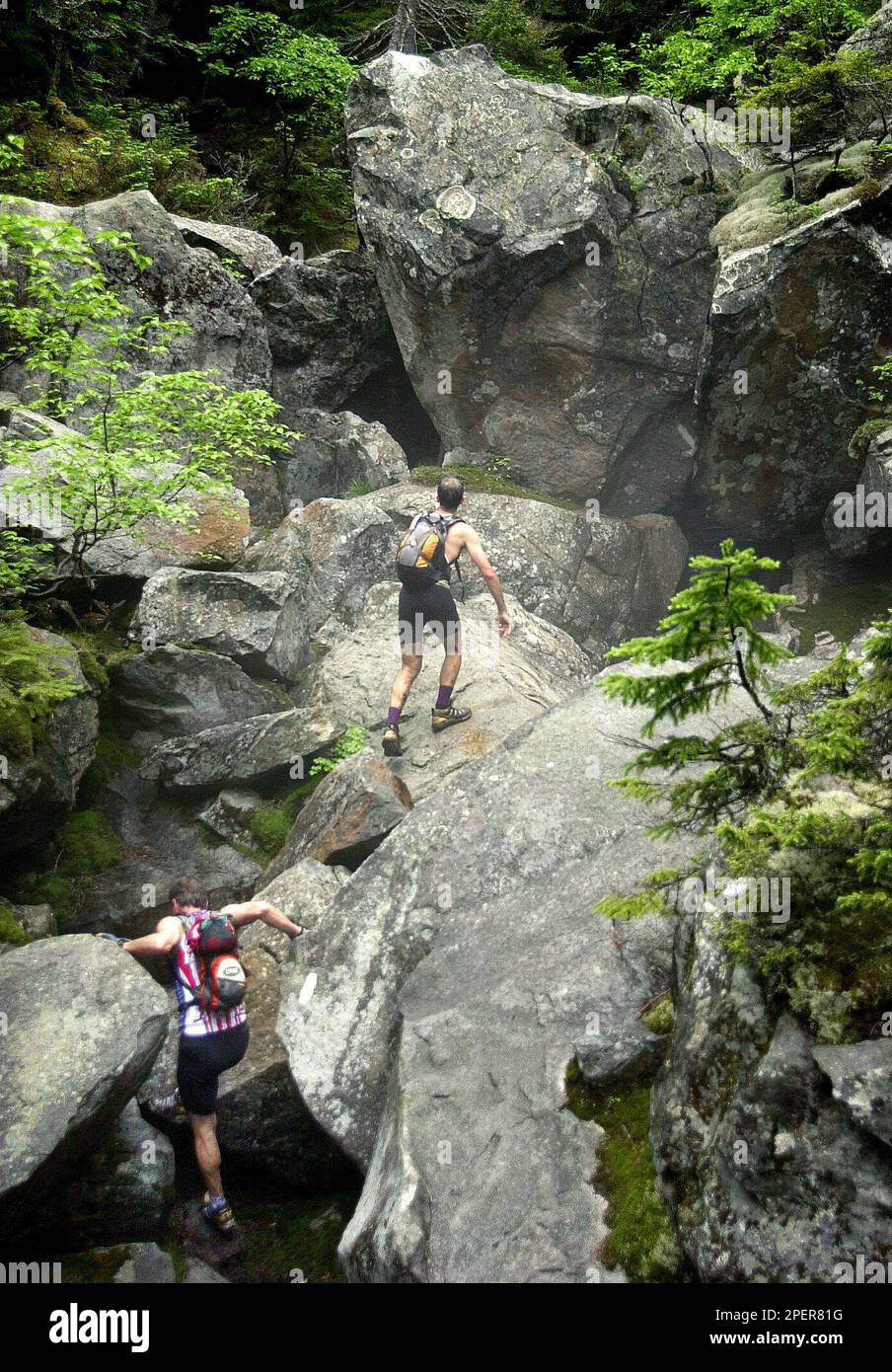 A pair of hikers scramble through a jumble of boulders on the ...