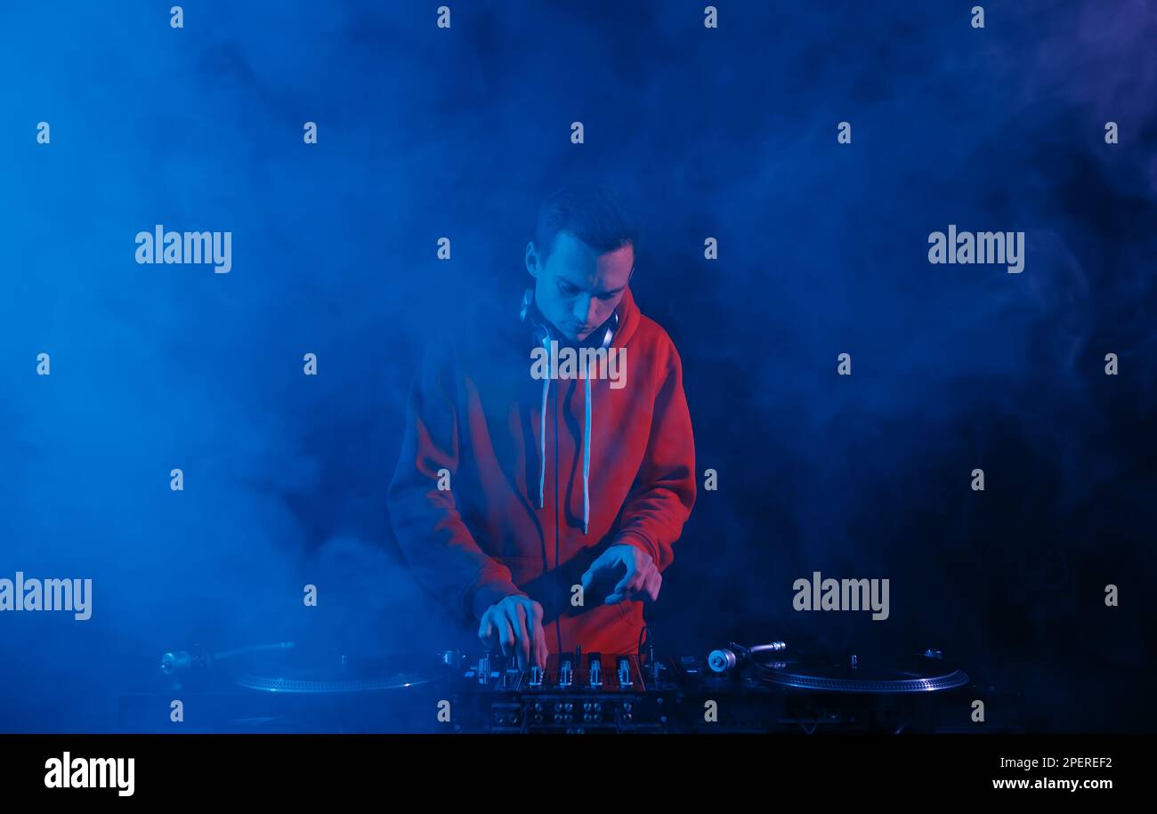 Party DJ mixing musical tracks in the club. Cool young disc jockey ...