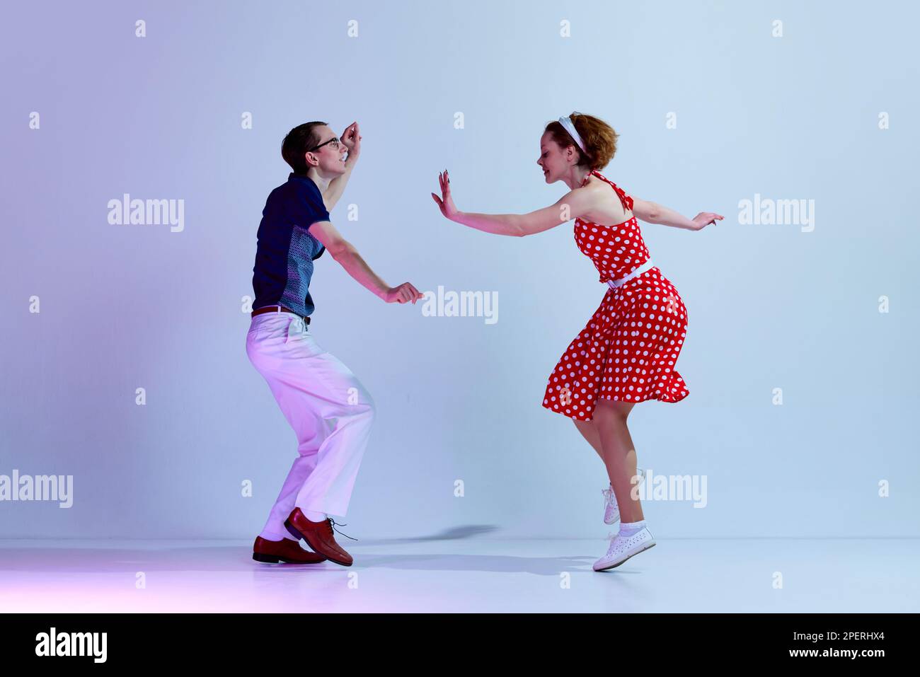Positive energy. Young girl and man in colorful costumes dancing social dances against gradient ...