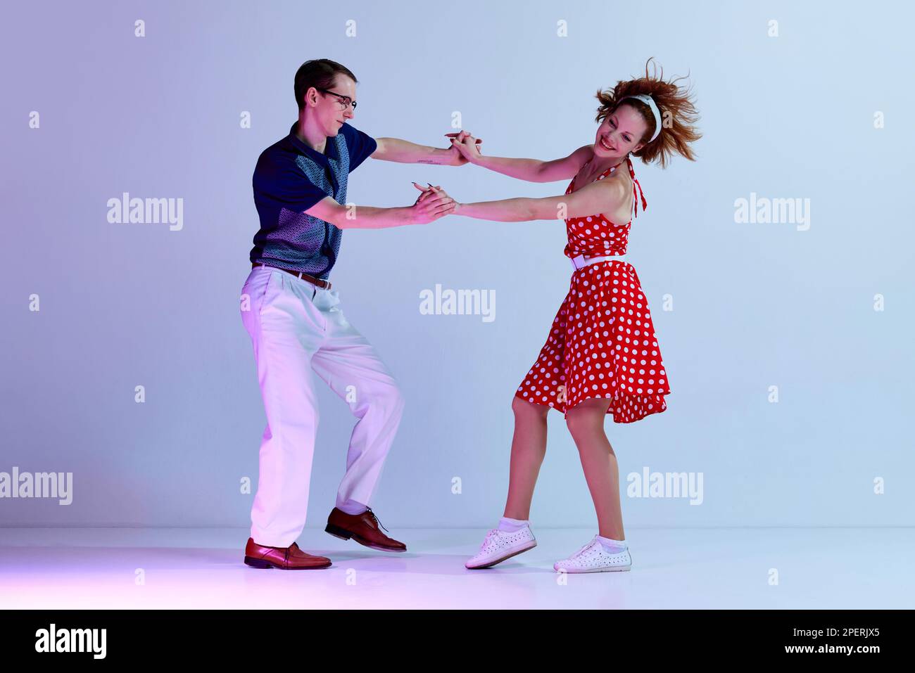 Positive energy. Young girl and man in colorful costumes dancing social dances against gradient ...