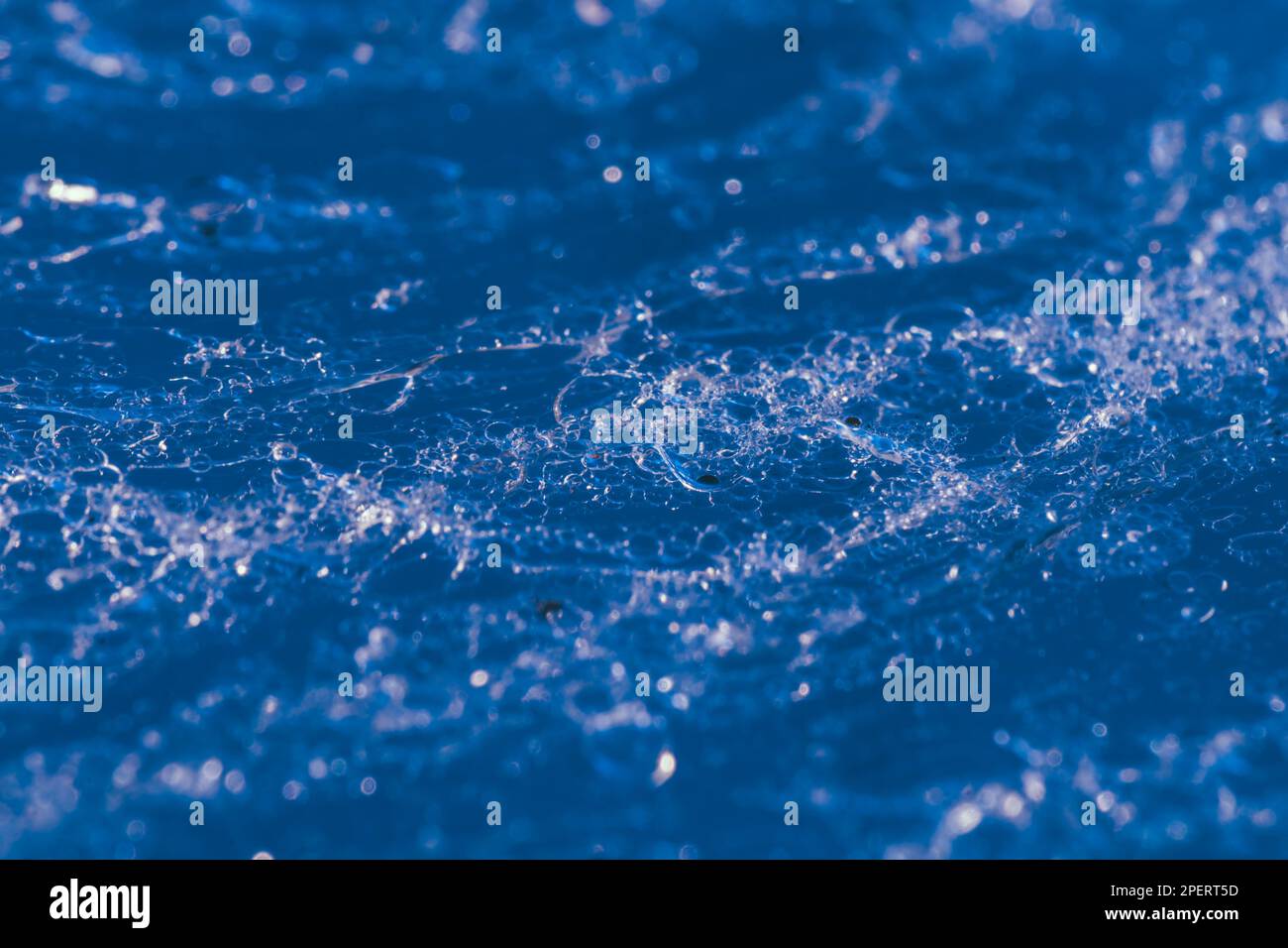 A closeup of blue translucent soap bubbles floating on the water ...