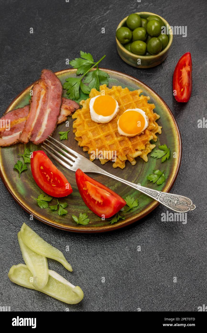 Two slices of tomato, waffles, fried bacon and two eggs, a fork on a ...