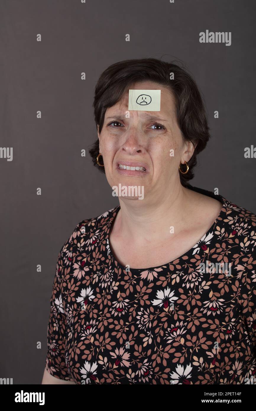 Woman in Pain with a sad face sticker on her head Stock Photo - Alamy