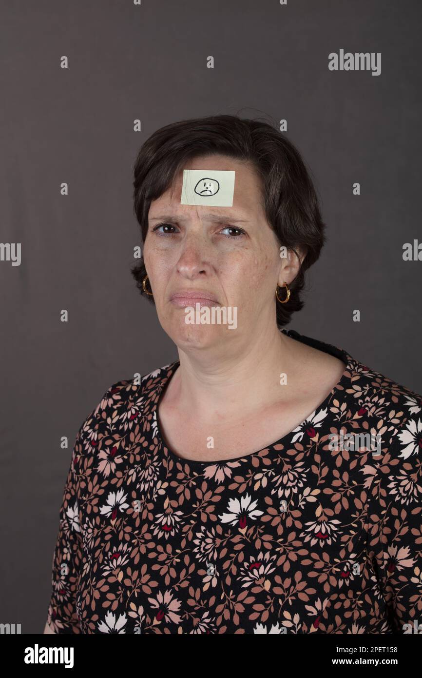 Woman in Pain with a sad face sticker on her head Stock Photo - Alamy