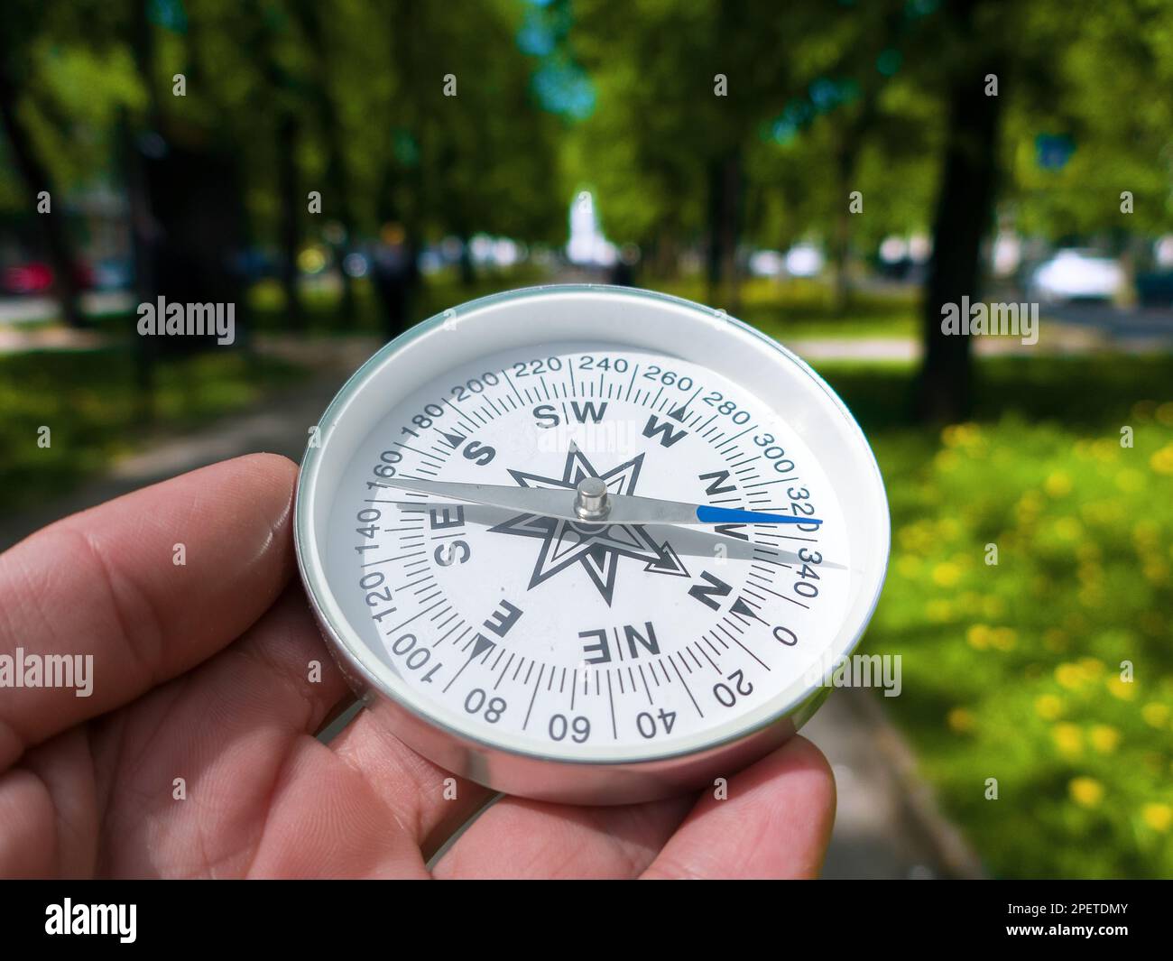 A compass in person's hand in park. Orient yourself in current ...