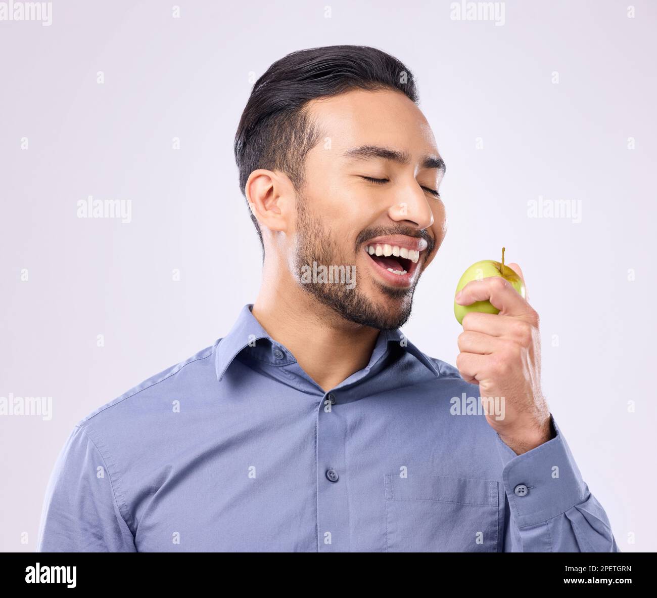 Hungry, eating and an Asian man with an apple isolated on a white ...