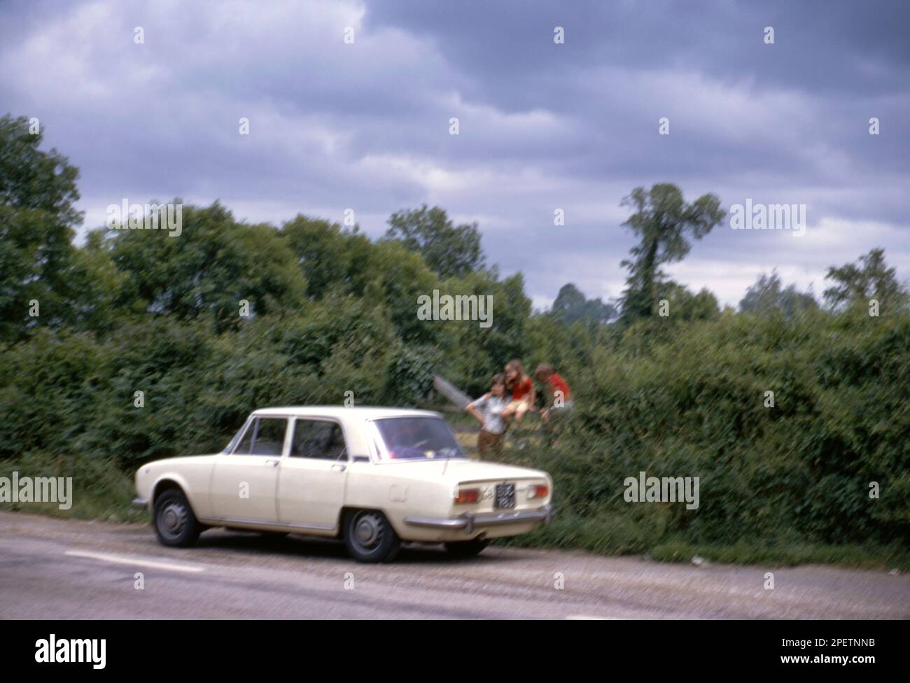 A young mum with her two small children sitting on a wooden gate into a ...