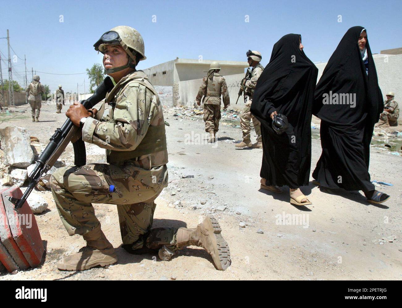 Iraqi women walk past Iraqi Army 2nd Battalion soldiers on patrol in ...