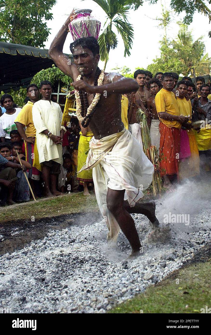 An Indonesian Hindu priest walks barefoot on hot coals during Theemithi ...