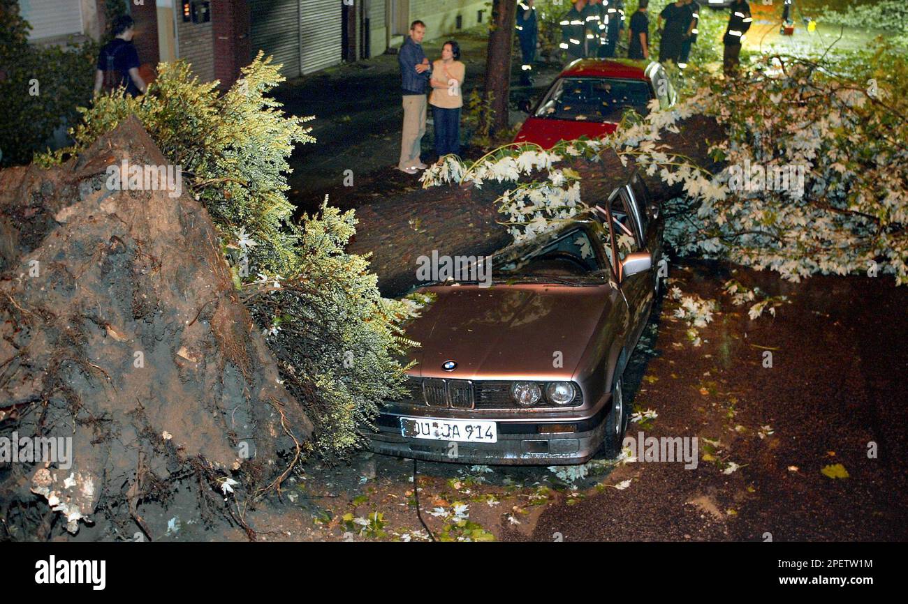 An uprooted tree lies on a car, late Sunday July 18, 2004 in downtown ...