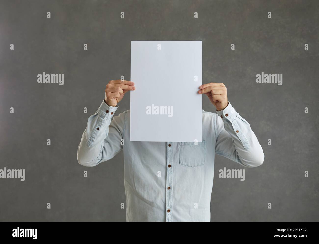 Man holds a white blank sheet of paper in front of him Stock Photo - Alamy