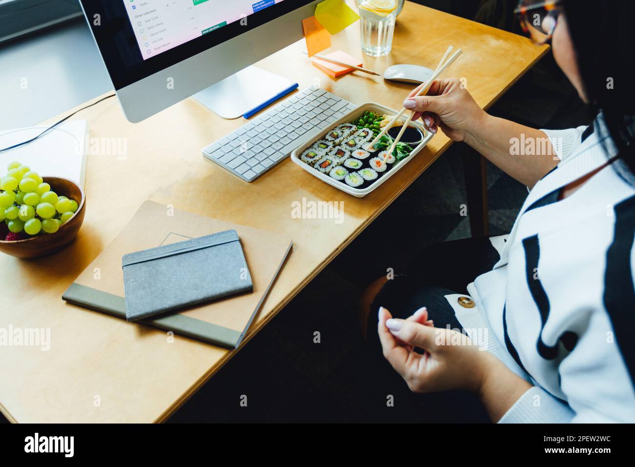 An office worker multitasks by eating sushi for lunch and concentrating ...