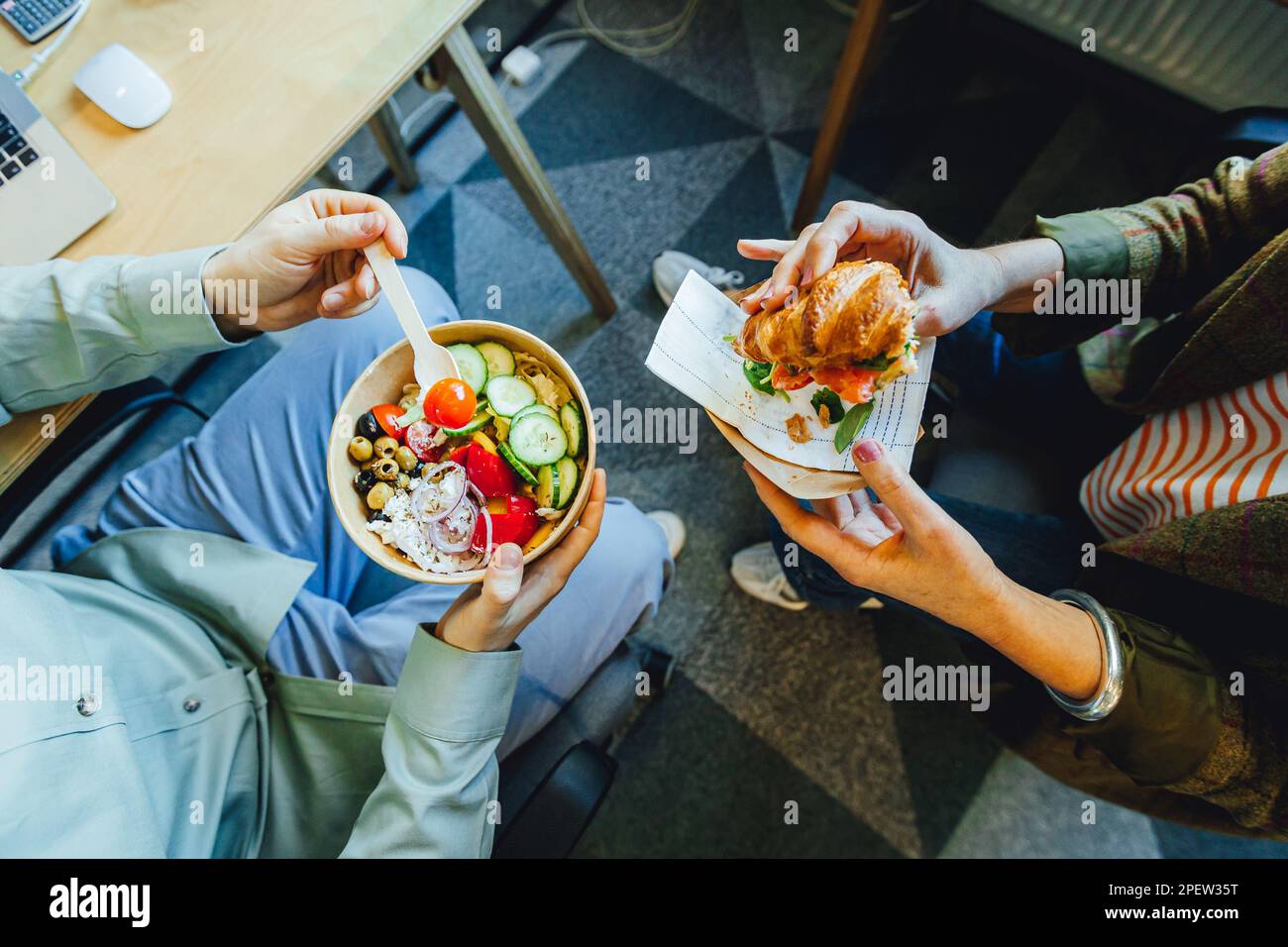 Two coworkers enjoying healthy lunch in the office, salad bowl and ...