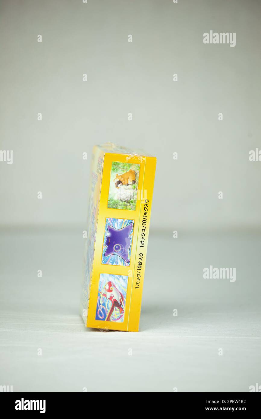 A vertical shot of a Pokemon one piece card game box against a grey ...