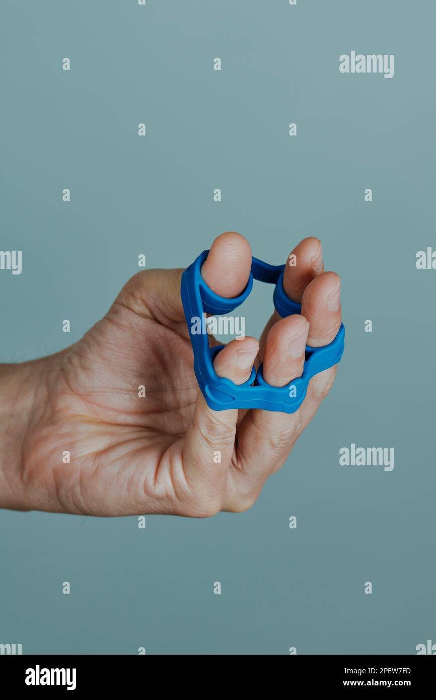 closeup of a man using a blue elastic band to exercise his fingers on a ...