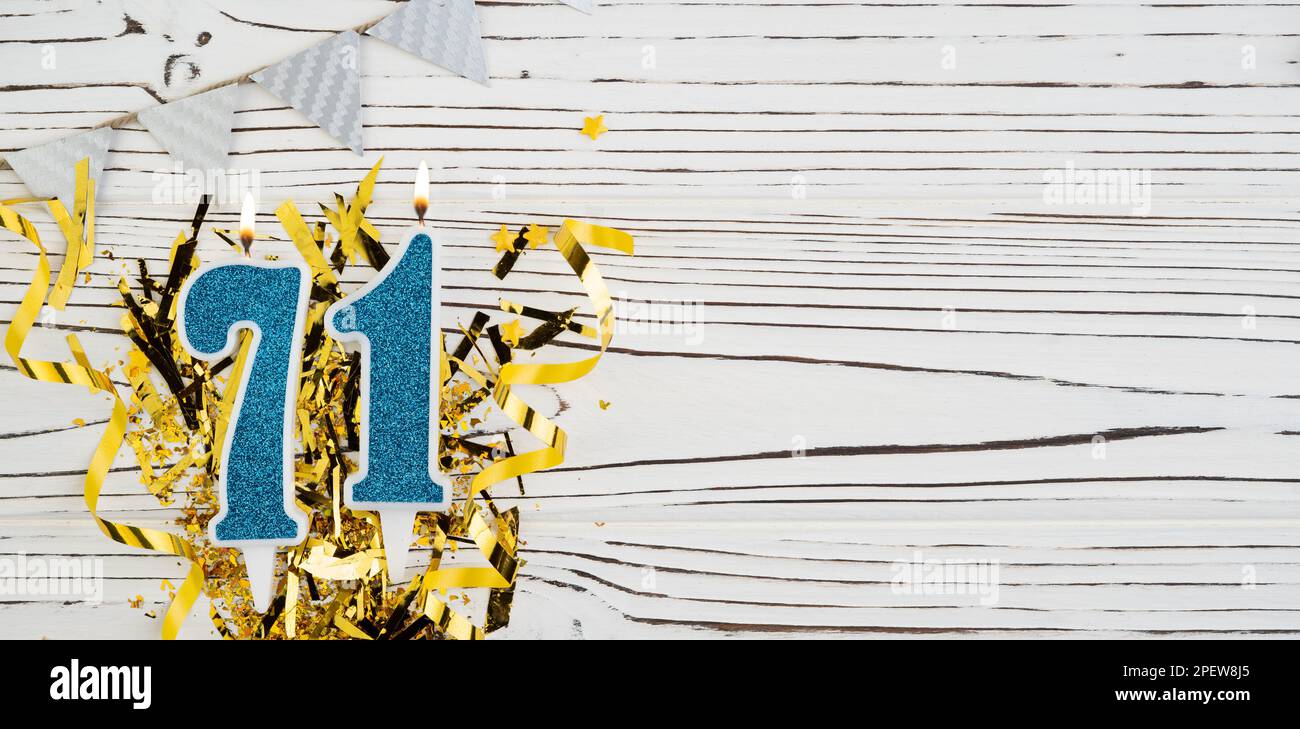 Number 71 blue celebration candle on white wooden background with ...