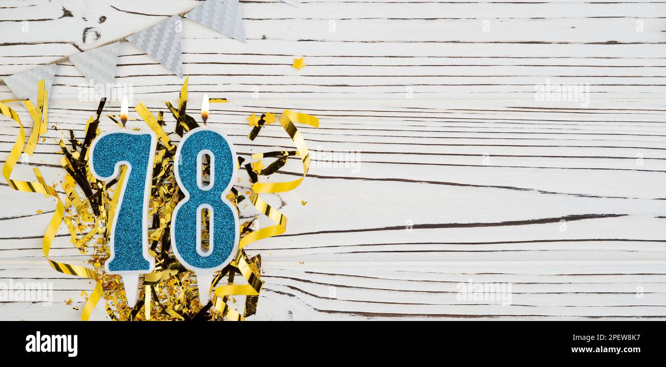 Number 78 blue celebration candle on white wooden background with ...