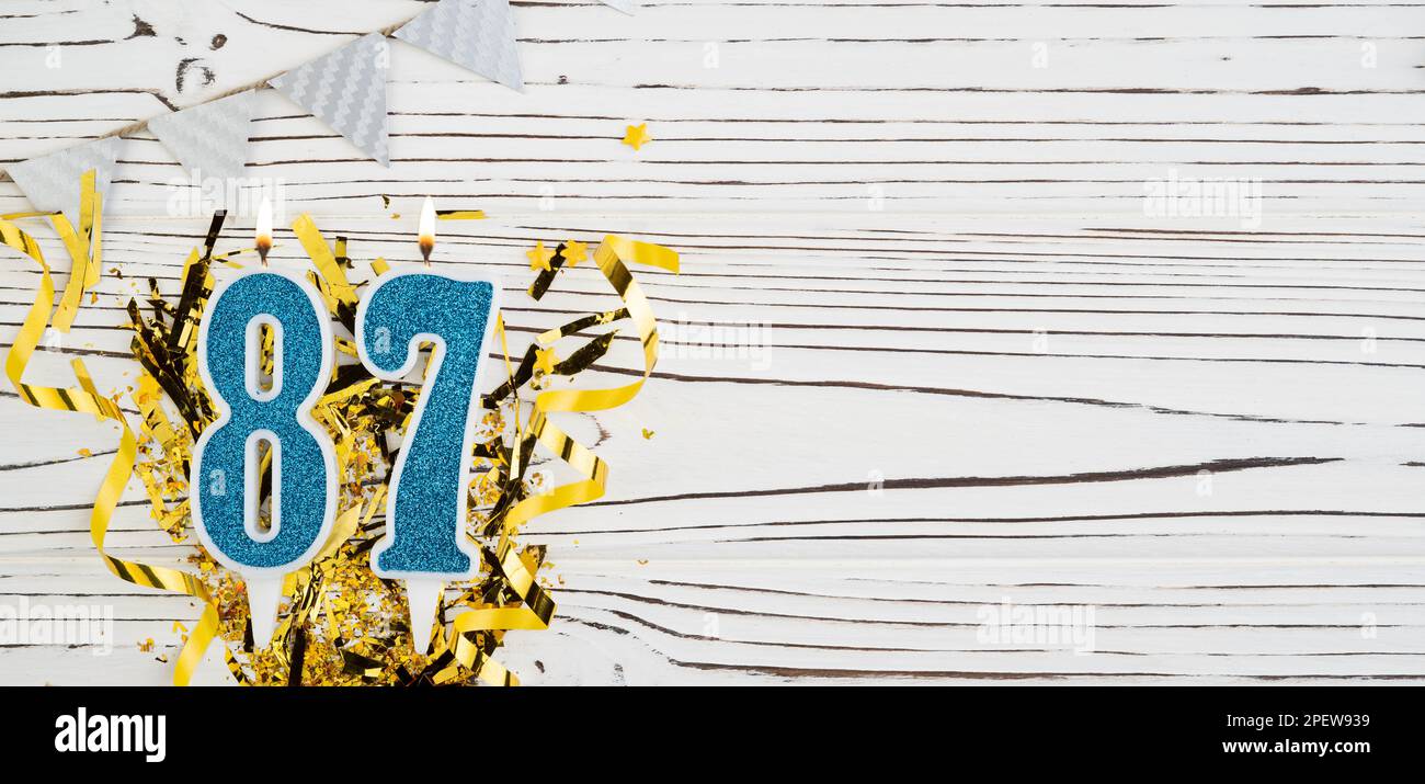 Number 87 blue celebration candle on white wooden background. Happy ...
