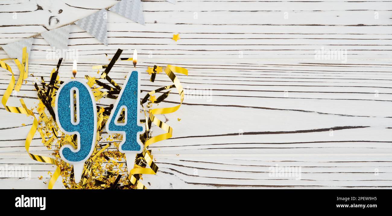 Number 94 blue celebration candle on white wooden background. Happy ...