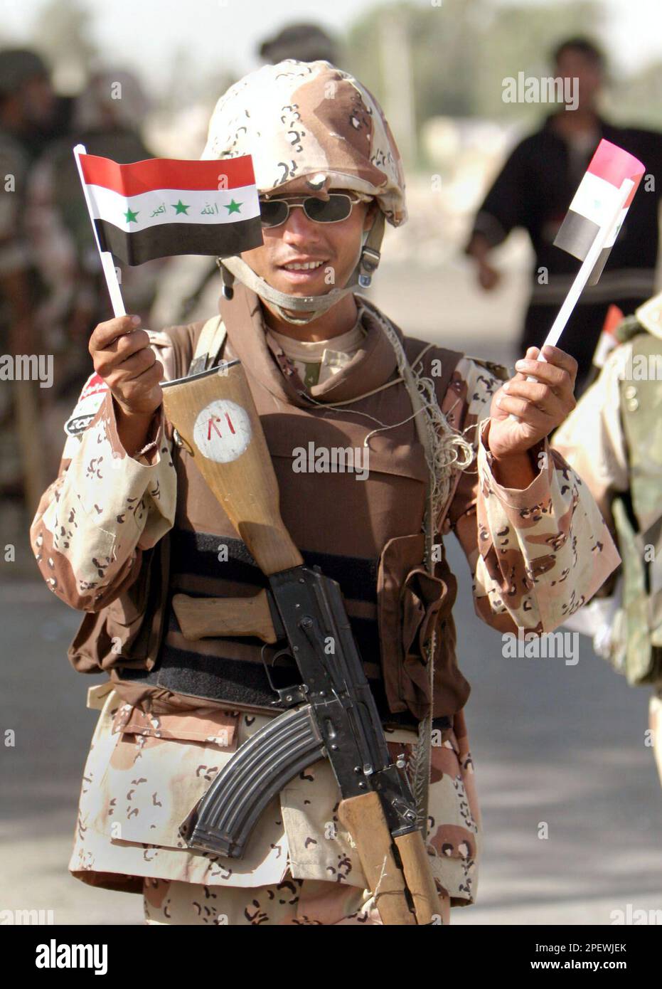 An Iraqi National Guard soldier waves Iraqi flags which were supplied ...