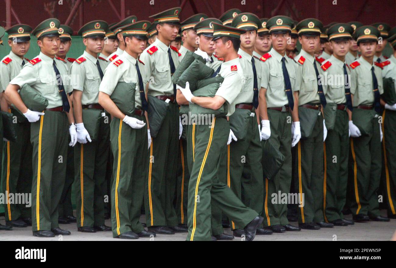 A Chinese paramilitary officer collects rain coats from his colleagues ...