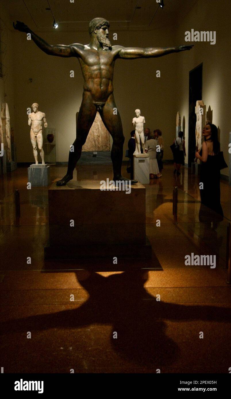 A visitor admires an ancient Greek statue, the Poseidon of Artemision ...