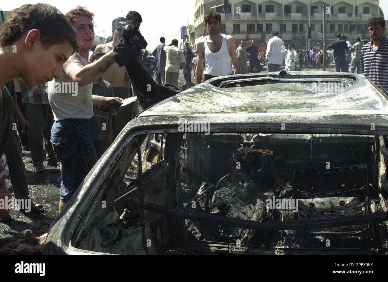 An Iraqi pulls a smoulding piece of clothing from a destroyed vehicle ...