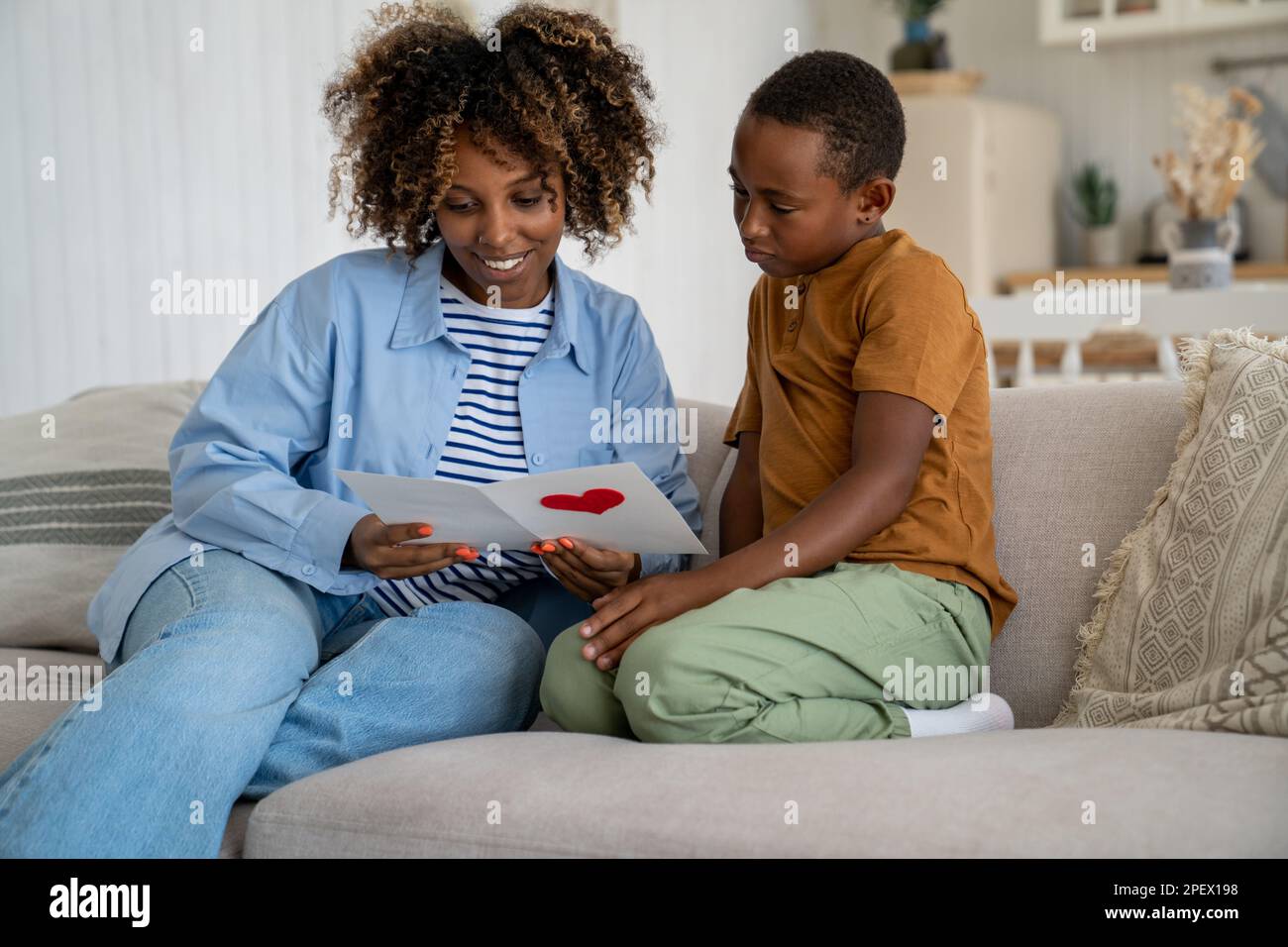 African American boy son giving handmade Mothers Day card to happy ...