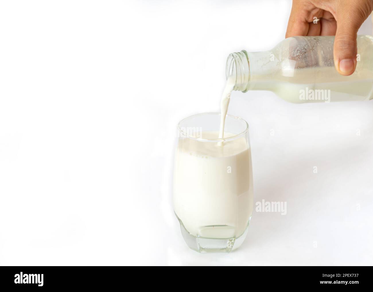 Close up hand hold bottle pouring milk to glass on isolate white ...