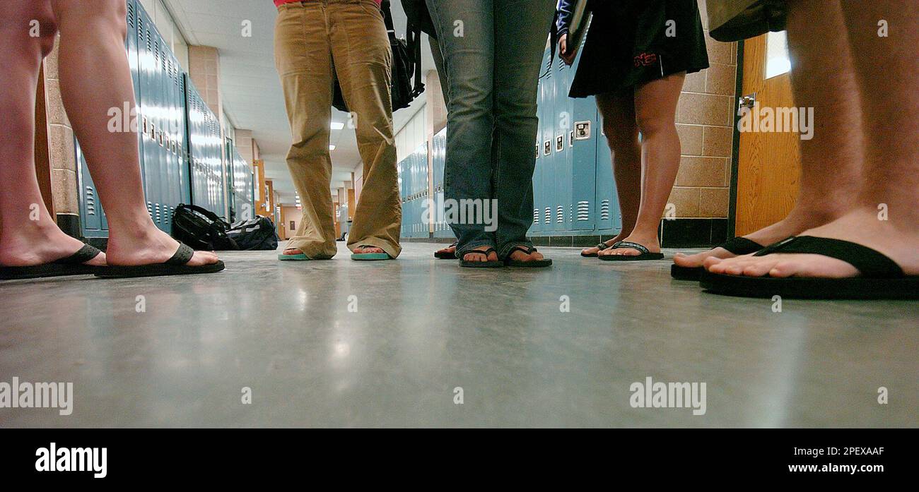 Students wearing flip flops hang out in a hallway during class change ...