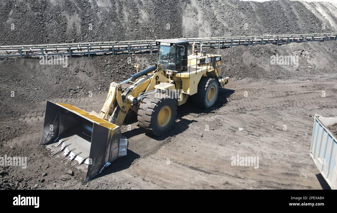 Wheel Loader loading coal on trucks, working at a huge mining site ...