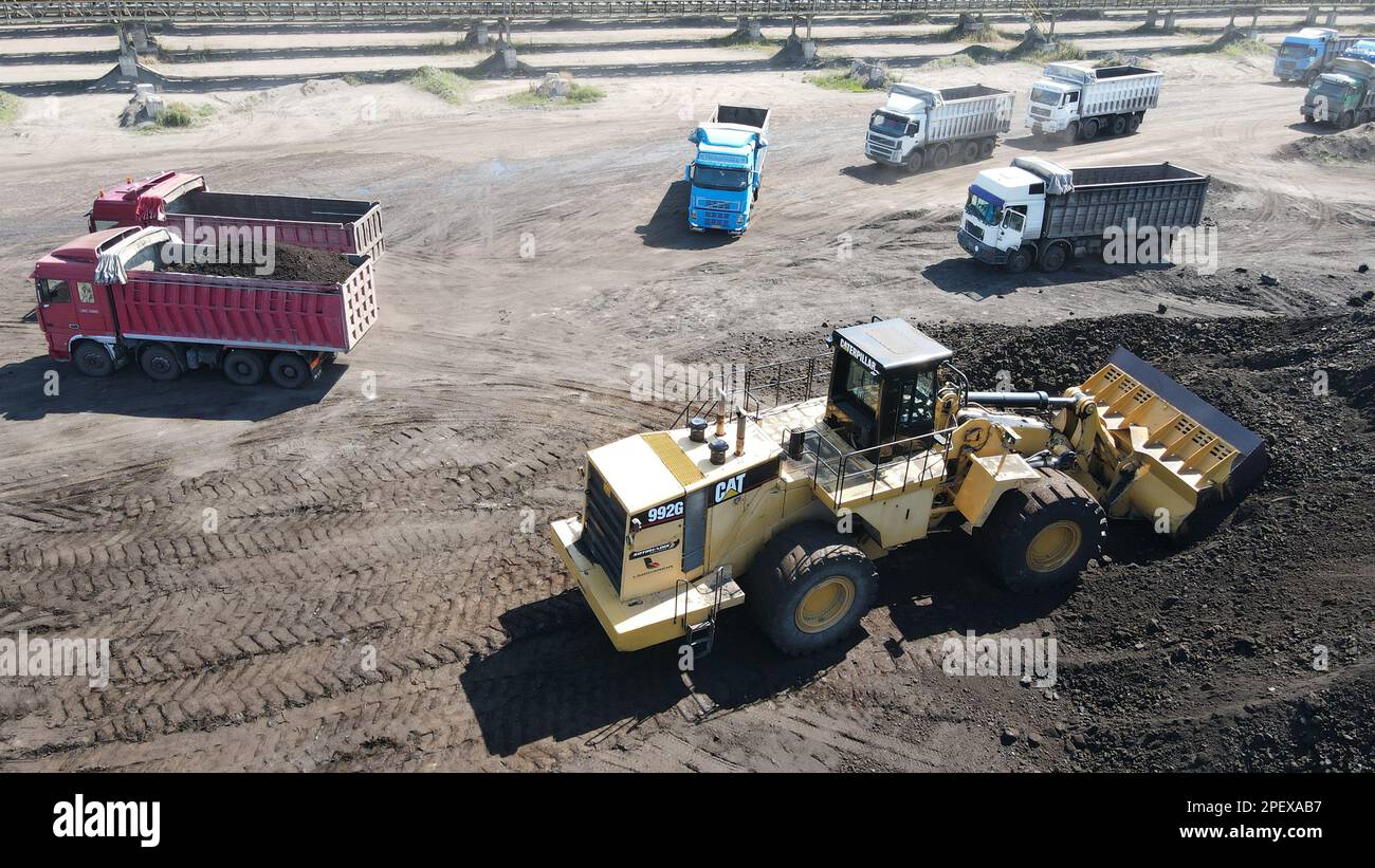 Wheel Loader loading coal on trucks, working at a huge mining site ...