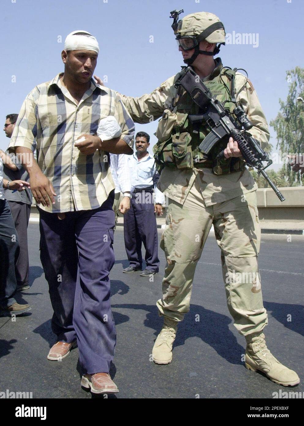 A U.S. soldier helps an injured Iraqi man to walk away from the scene ...