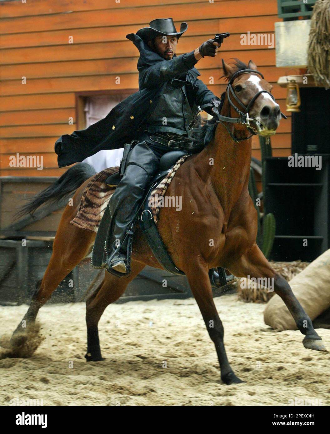 An Indonesian actor dressed in cowboy outfits points his pistol at a ...