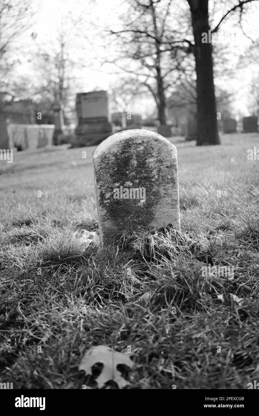 An old abandoned, weathered, and worn simple stone tombstone with a ...