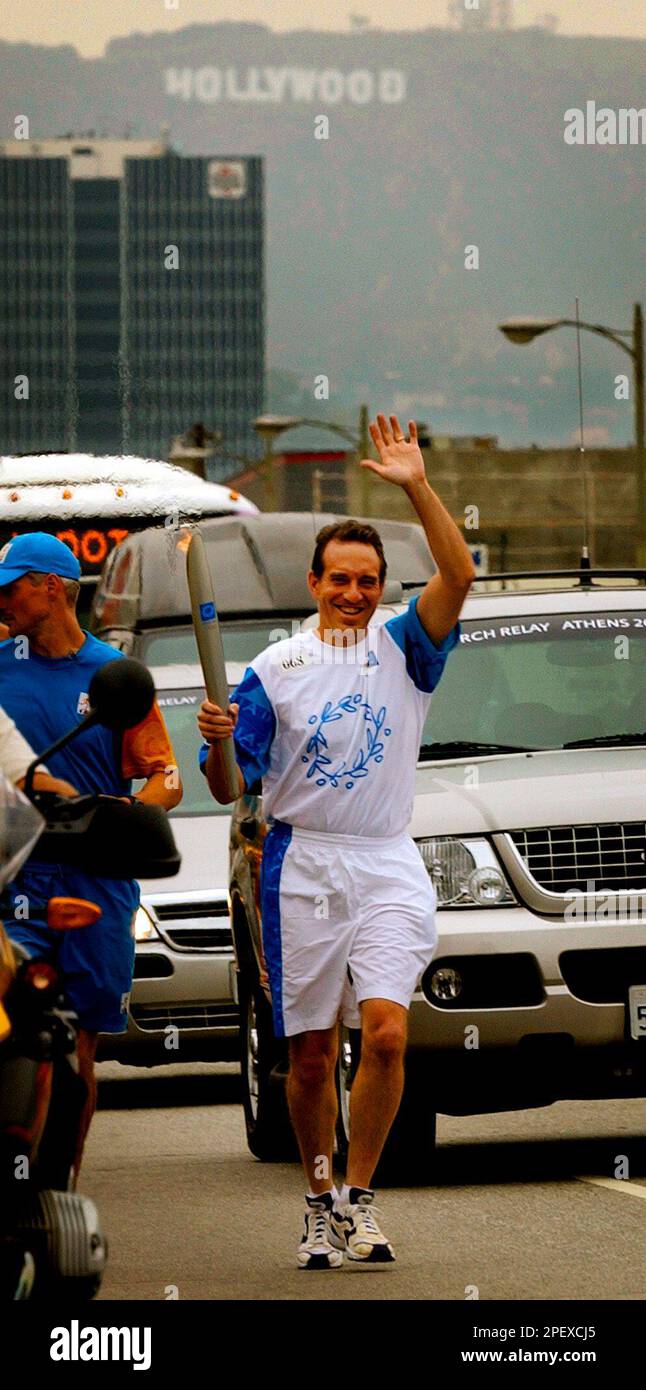 Coby King of Los Angeles waves as he carries his lit Olympic torch down ...