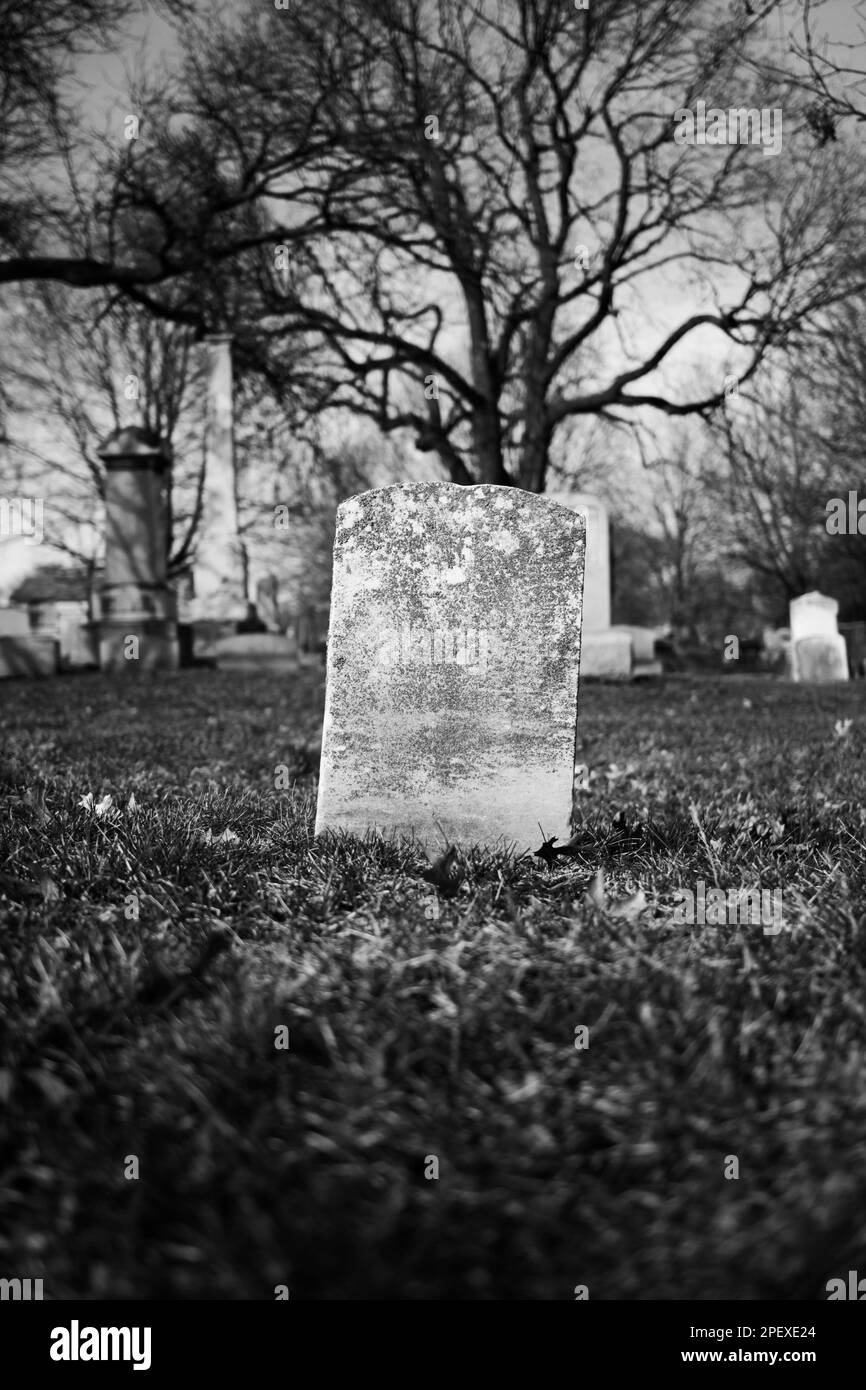 An old abandoned, weathered, and worn simple stone tombstone with a ...