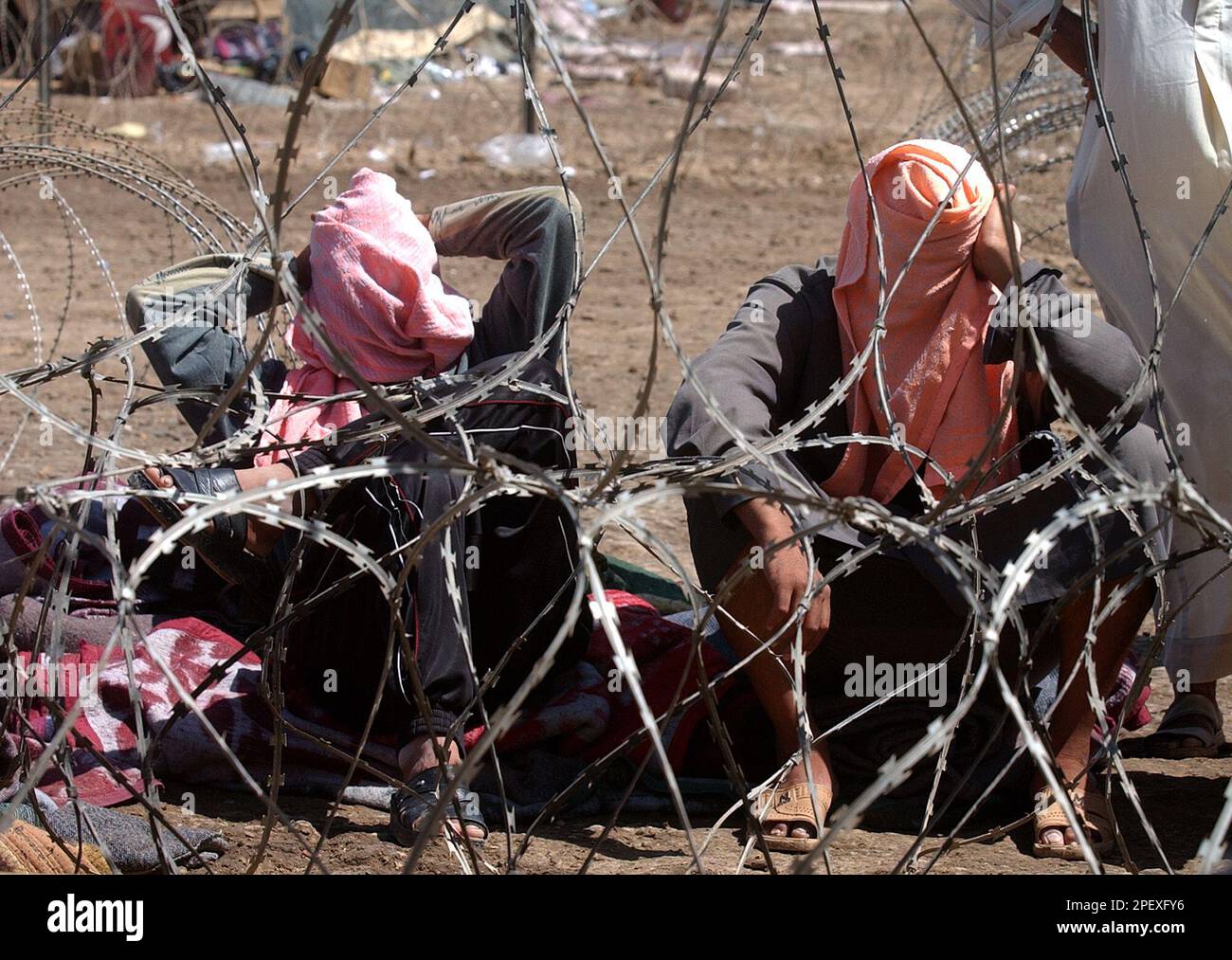 Iraqi prisoners, covering their heads to protect their identity, sit in ...