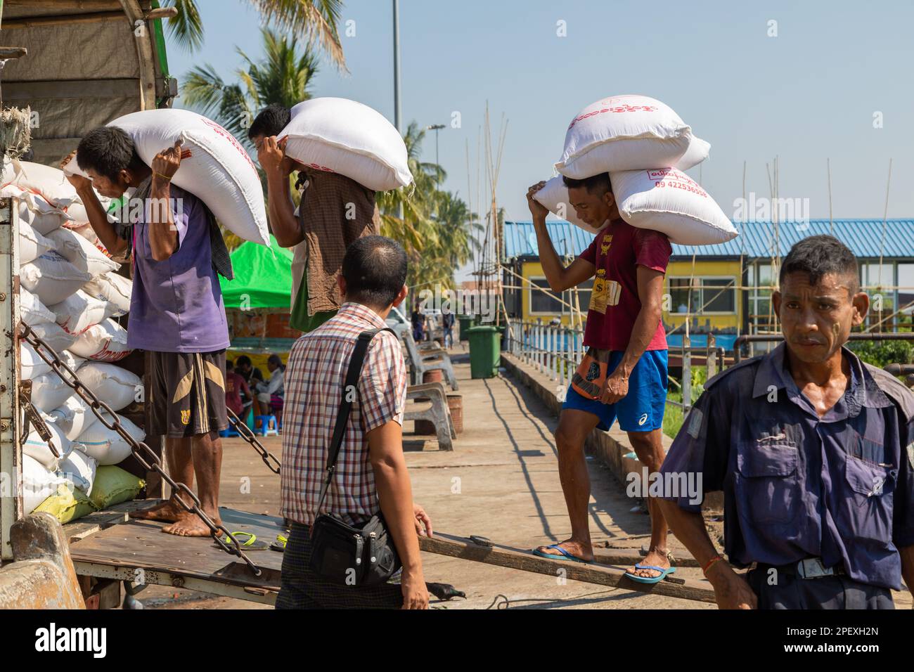Yangon, Myanmar - Dec 19, 2019: Men carry huge sacks of rice on their ...