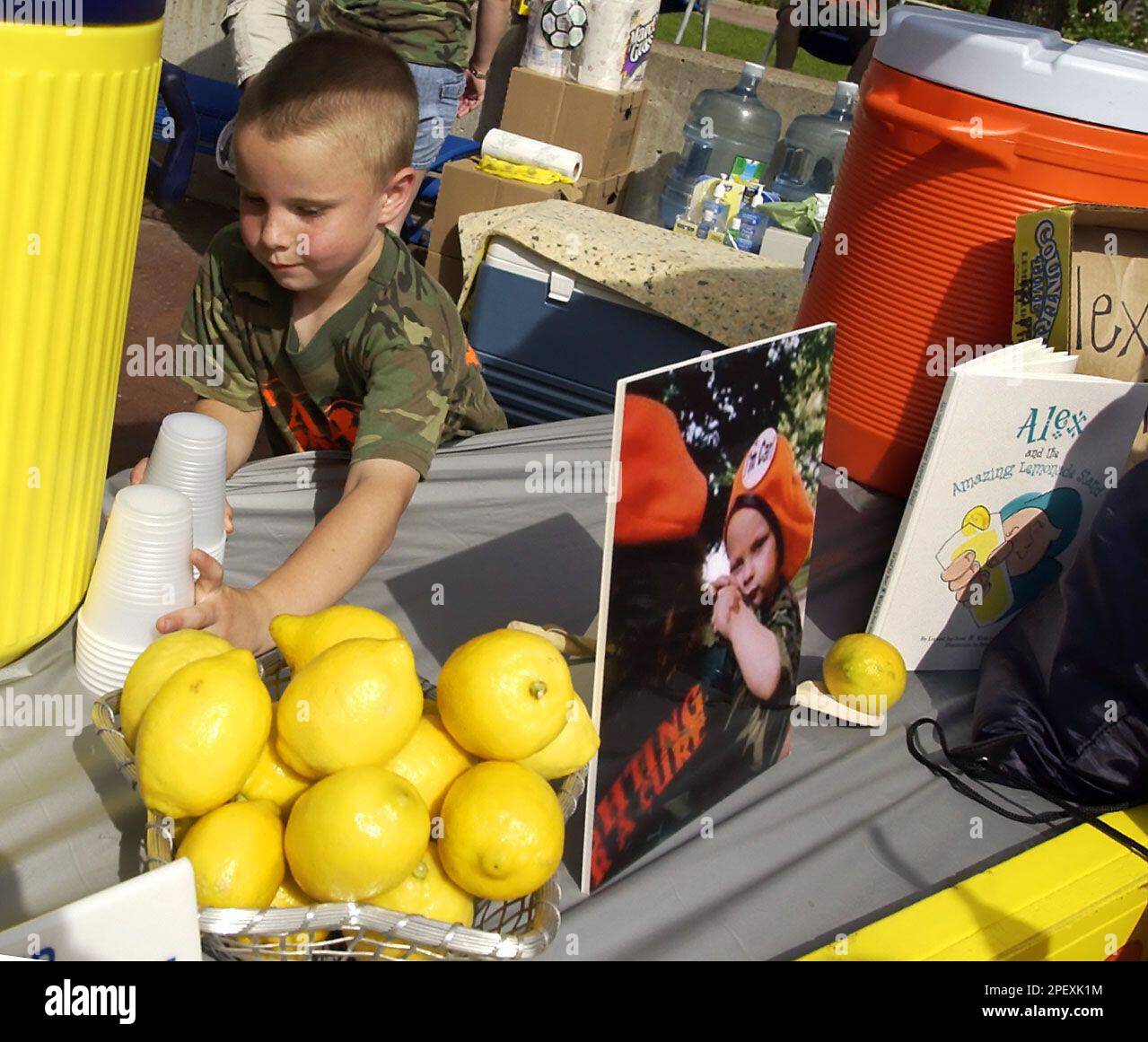 Five-year-old Sam Robinson reaches for some lemonade glasses as he ...