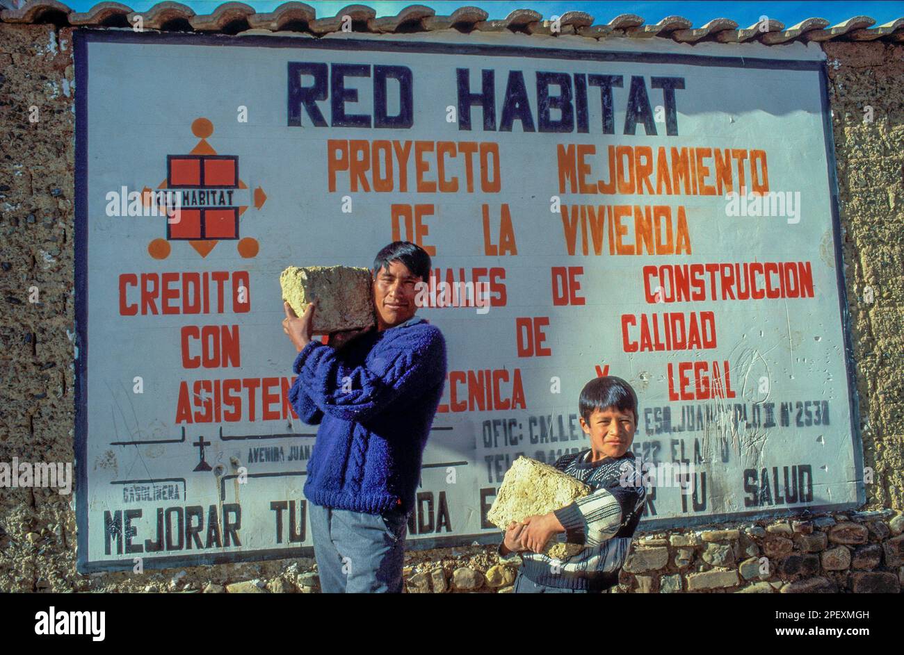 Bolivia, El Alto / La Paz. Father and son carry bricks in front of a ...