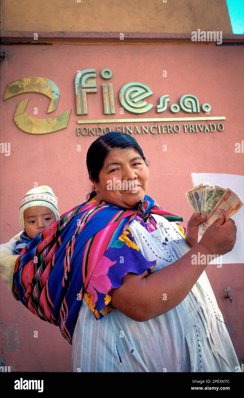 Bolivia, La Paz. Mother with baby has just received money from finance ...