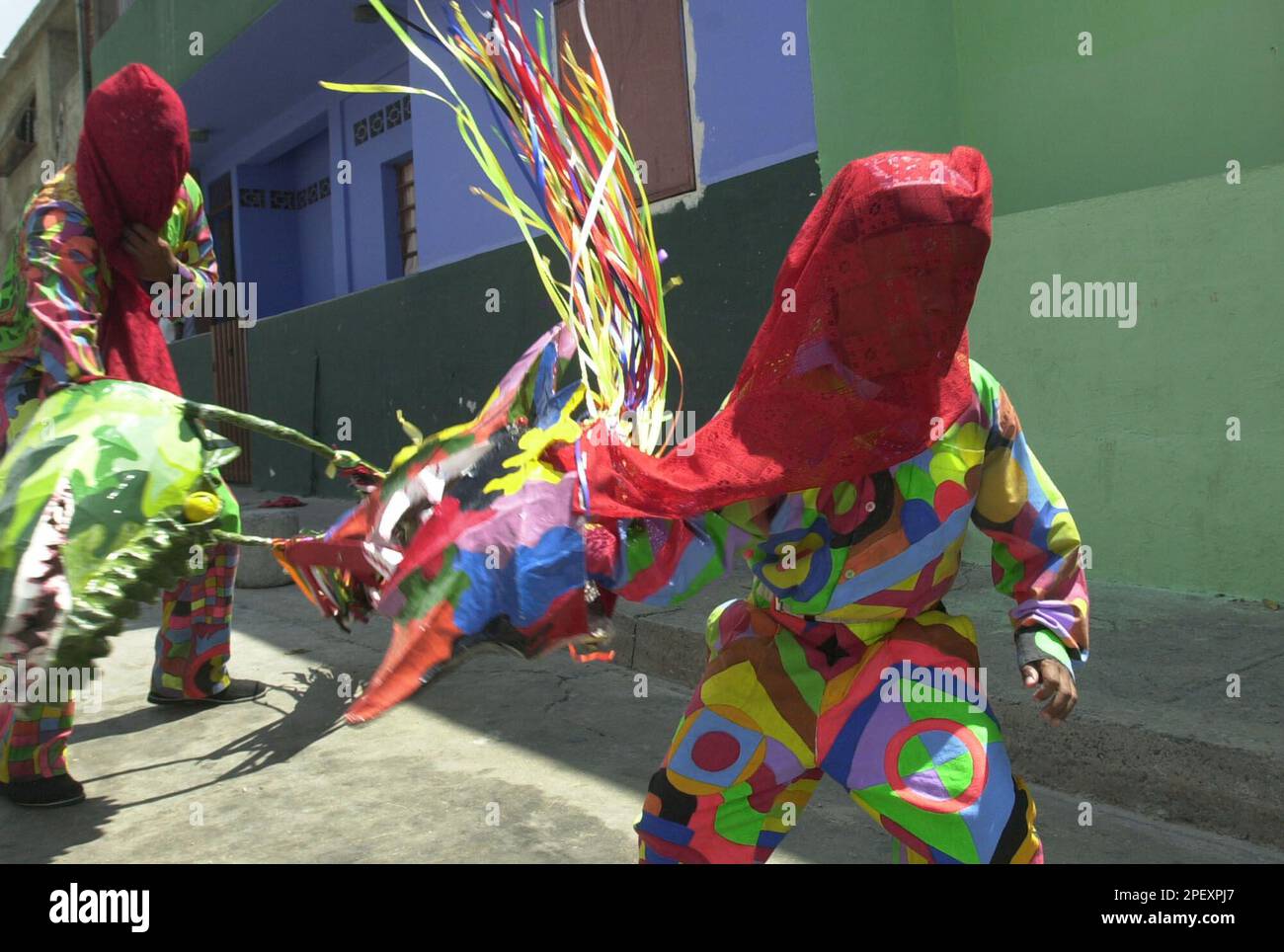 A young child dressed as a devil dances through the streets of Naiguata ...