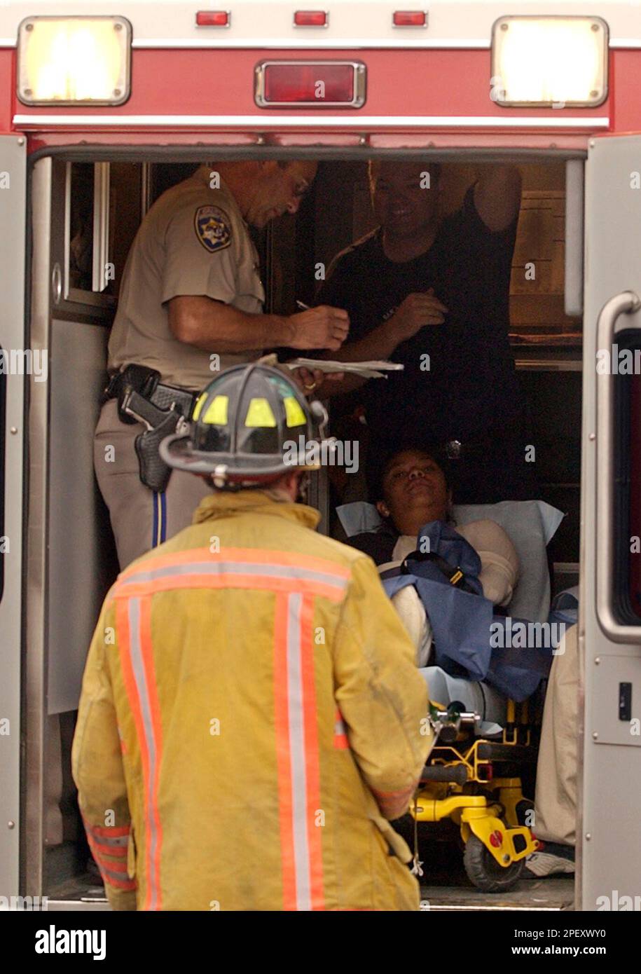 A firefighter and police officer help load an injured child into an ...