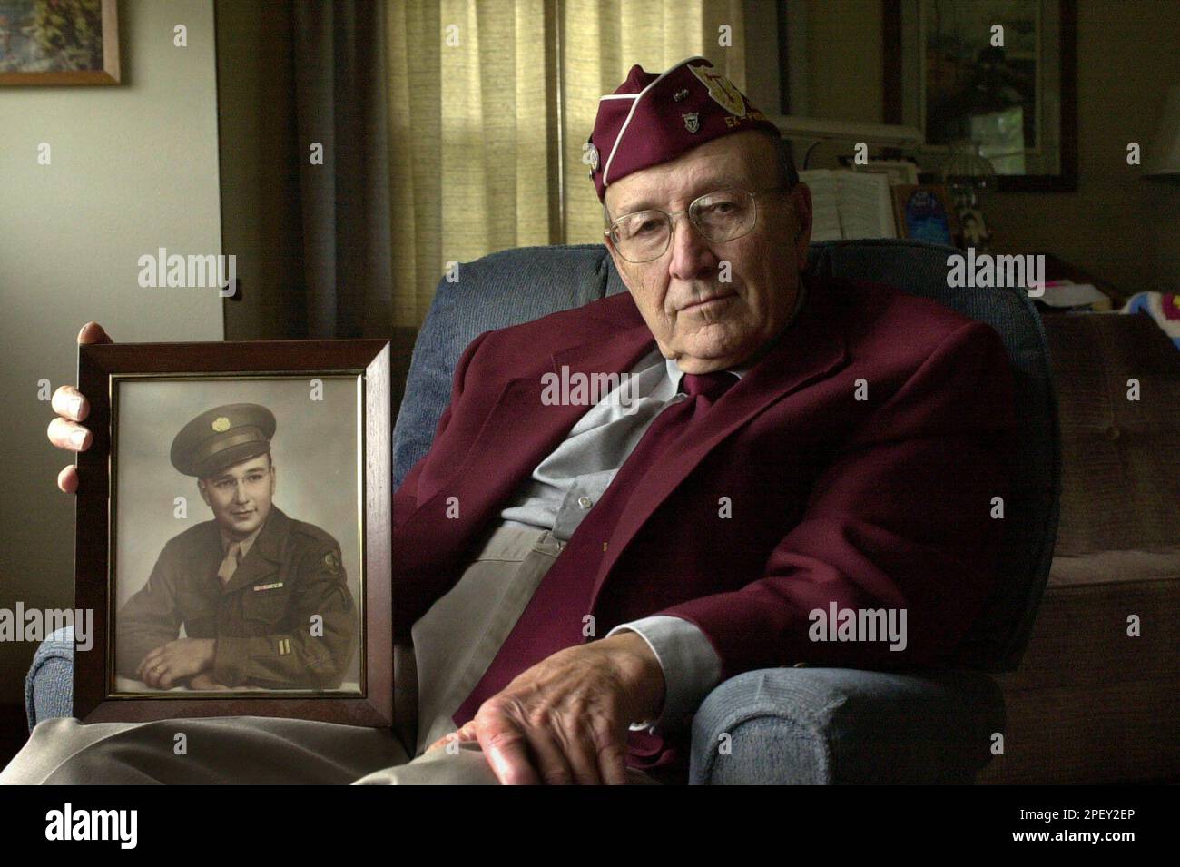 Former World War II prisoner of war Roy L. Olinger holds an old Army ...