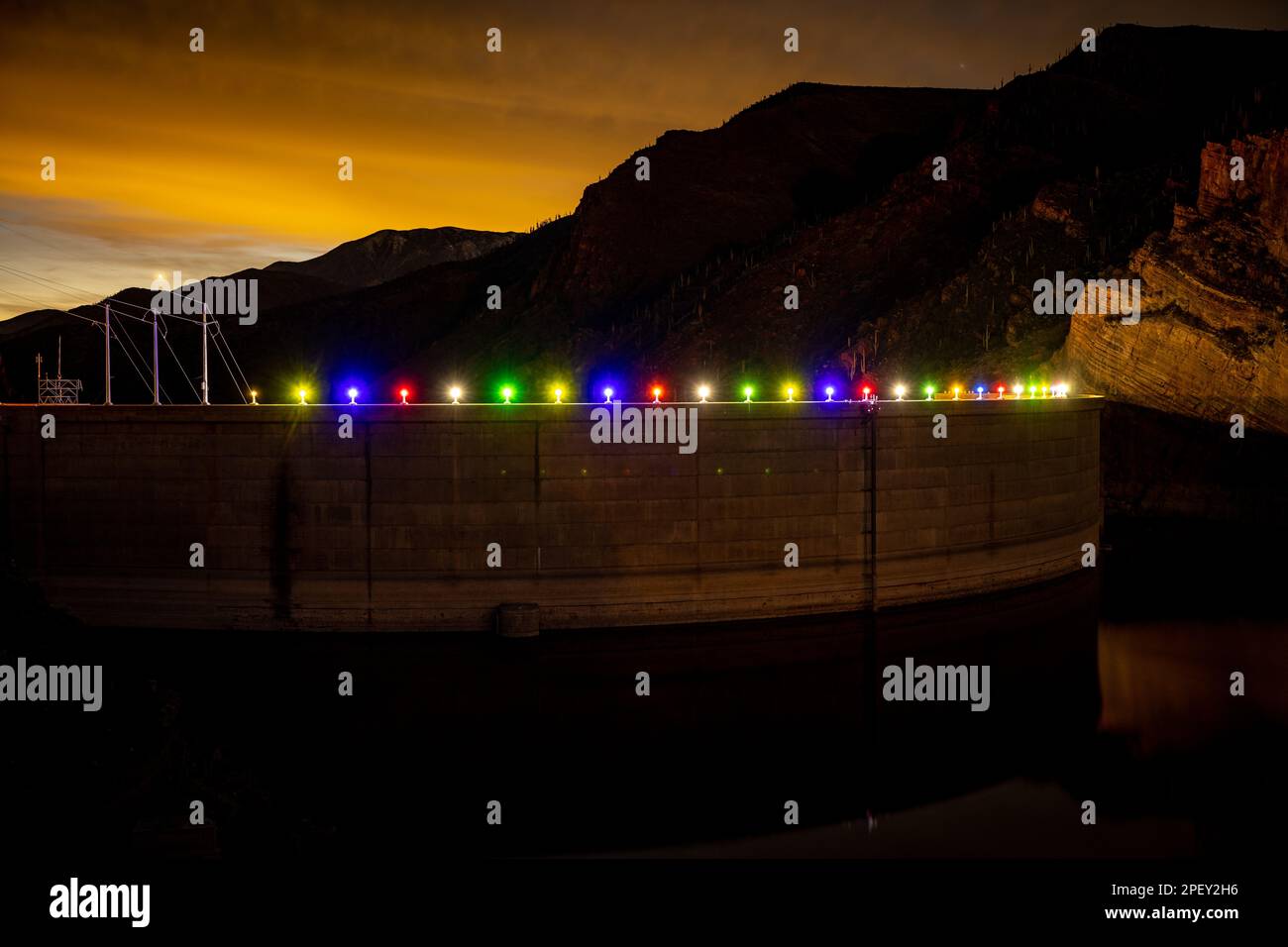 An illuminated dam with vibrant lights cascading down the sides ...