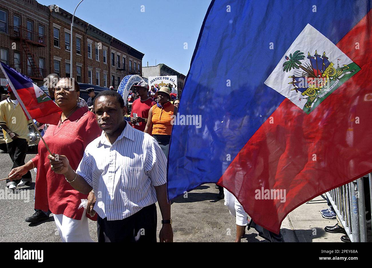A large Haitian flag flutters in the wind as revelers and floats pass ...
