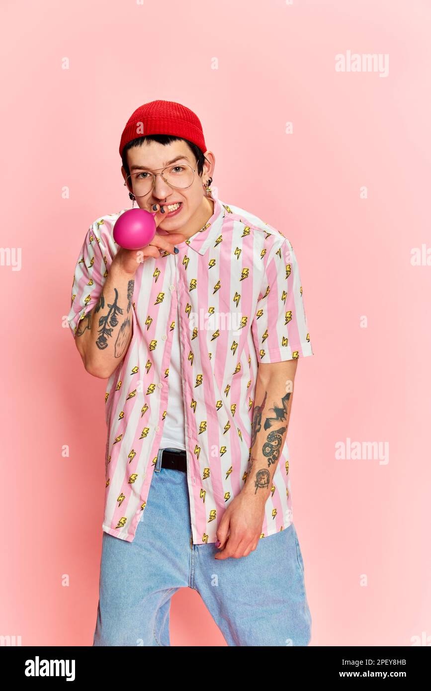 Funny stylish guy with tattoo puffing up the balloon like cigarettes ...