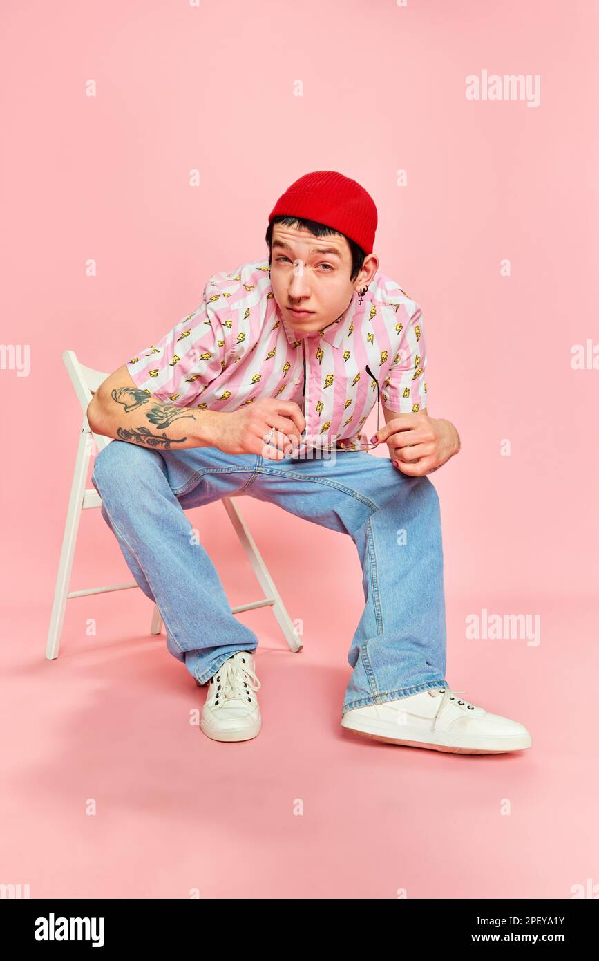 Stylish guy grimacing and leaning forward and posing while sitting on ...